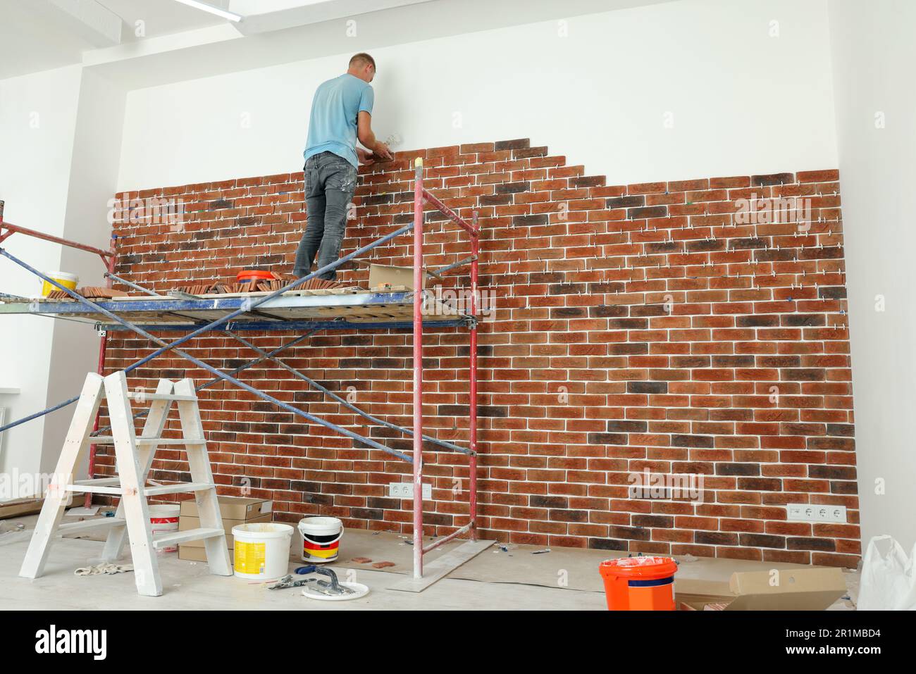Professional builder gluing decorative bricks on wall in room. Tiles ...