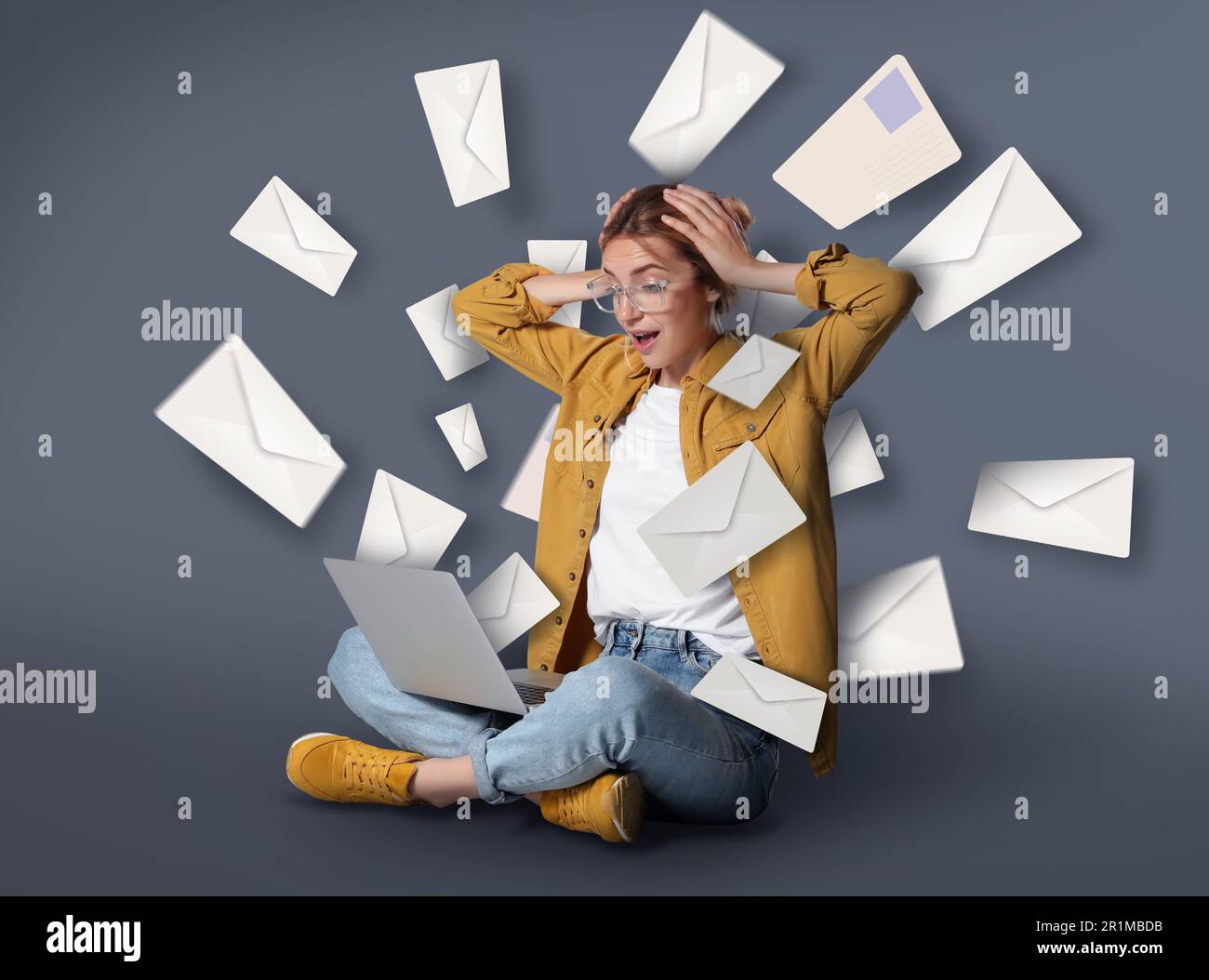 Email spam. Emotional young woman with laptop and many letters on grey ...