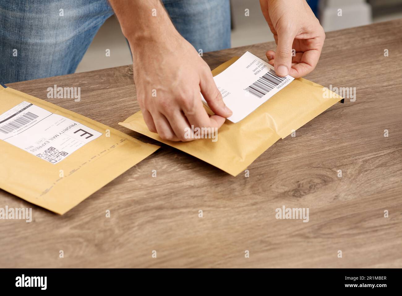 Post office worker sticking barcode on parcel at counter indoors ...