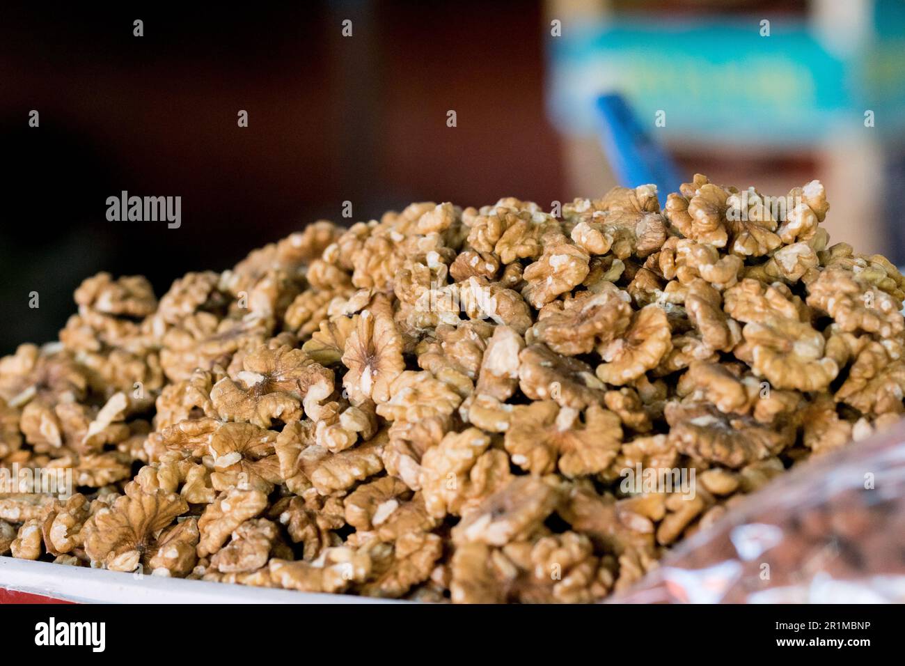 A pile of walnuts in a large container, for sale at a stall in a green ...
