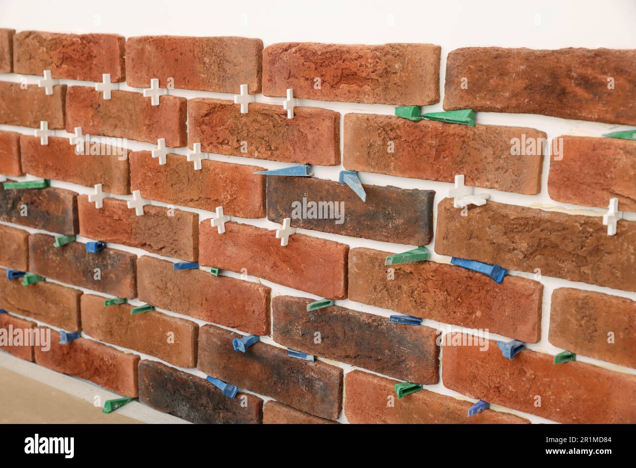 Decorative bricks with tile leveling system on white wall in room Stock ...
