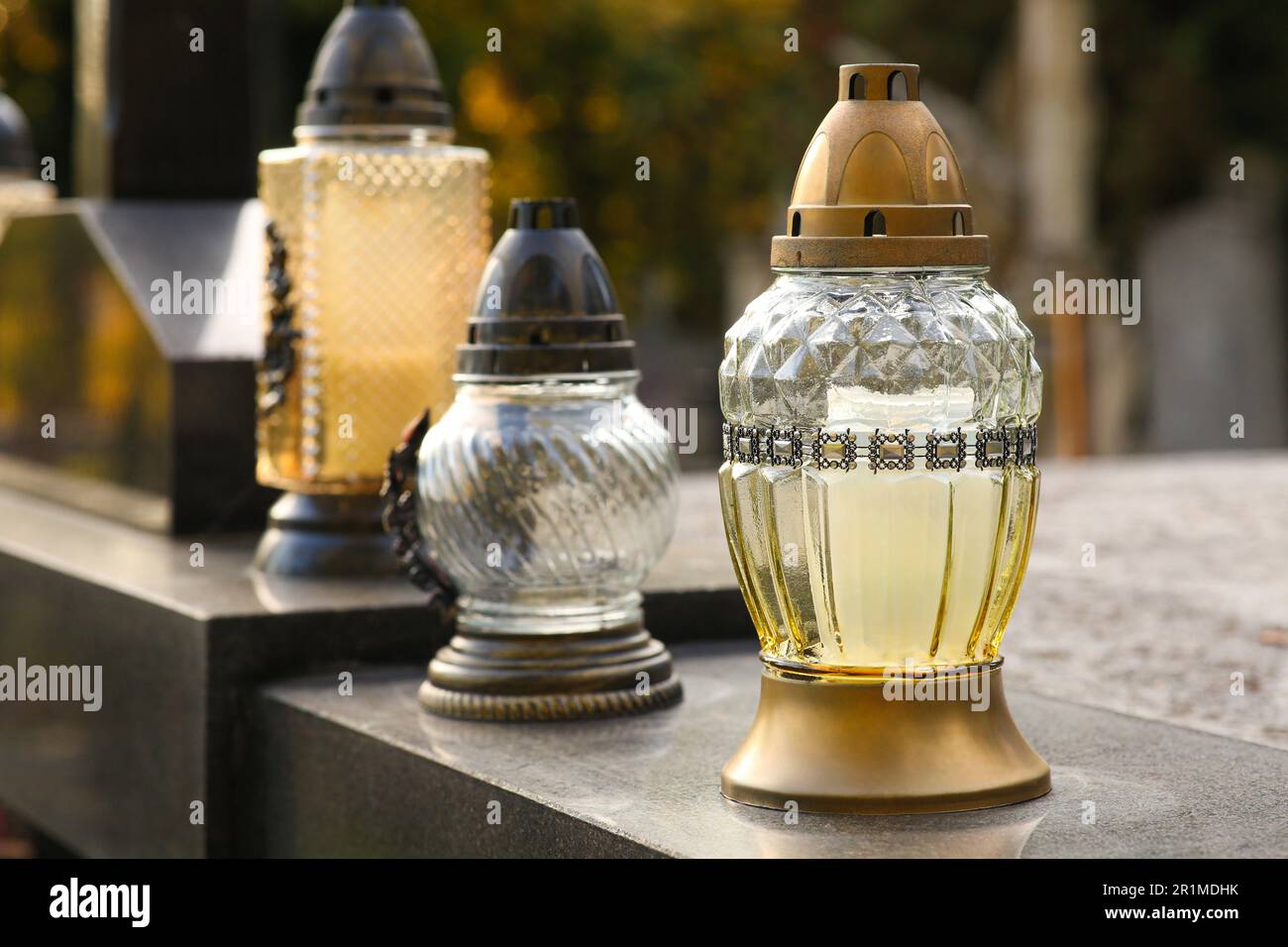 Different grave lanterns on granite tombstone outdoors, space for text. Funeral ceremony Stock ...