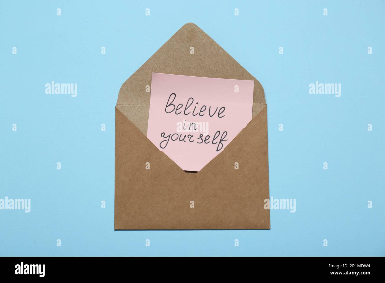 Envelope with message Believe In Yourself on light blue background, top ...
