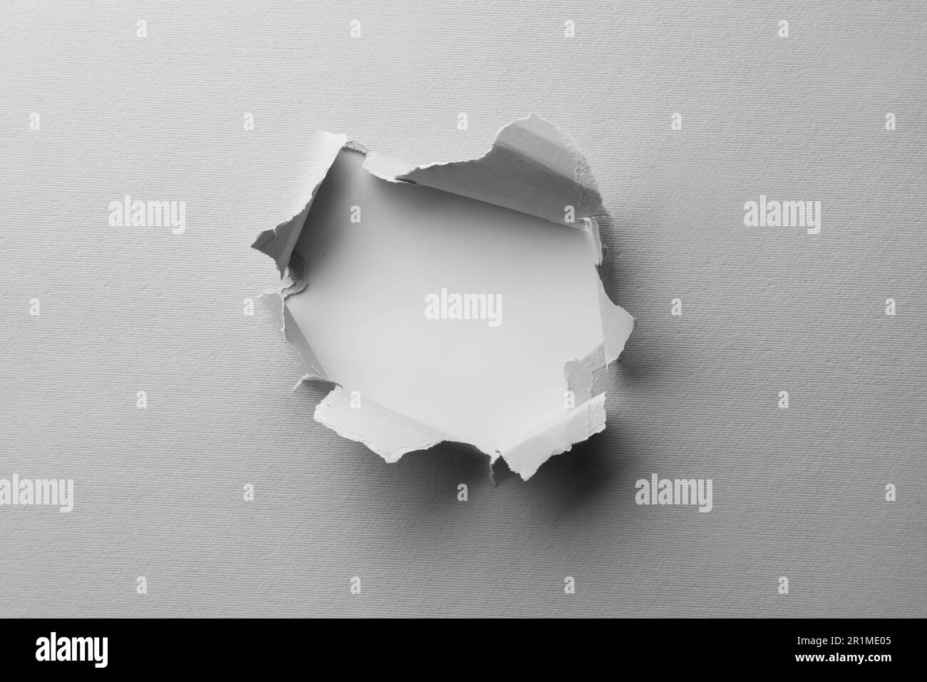 Hole in white paper on light background Stock Photo - Alamy