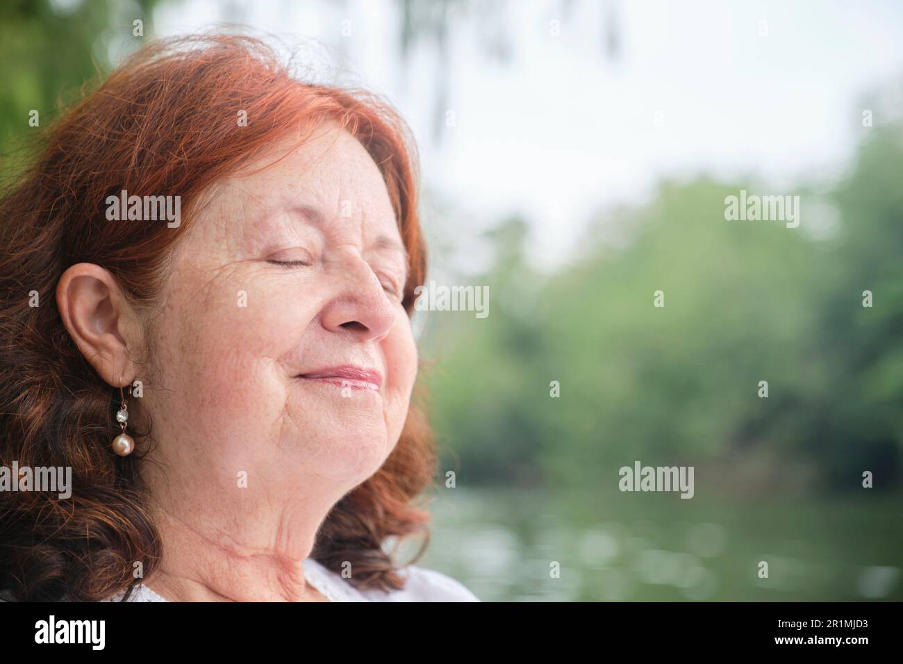 Portrait of a latin senior woman smiling carefree with eyes closed ...
