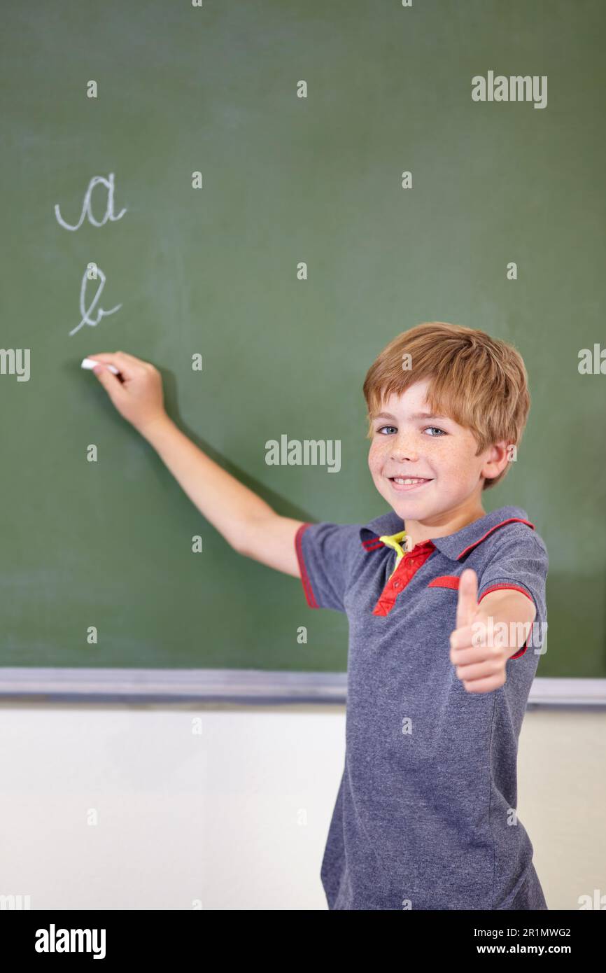 He knows the answer. A young boy writing on the blackboard at school ...