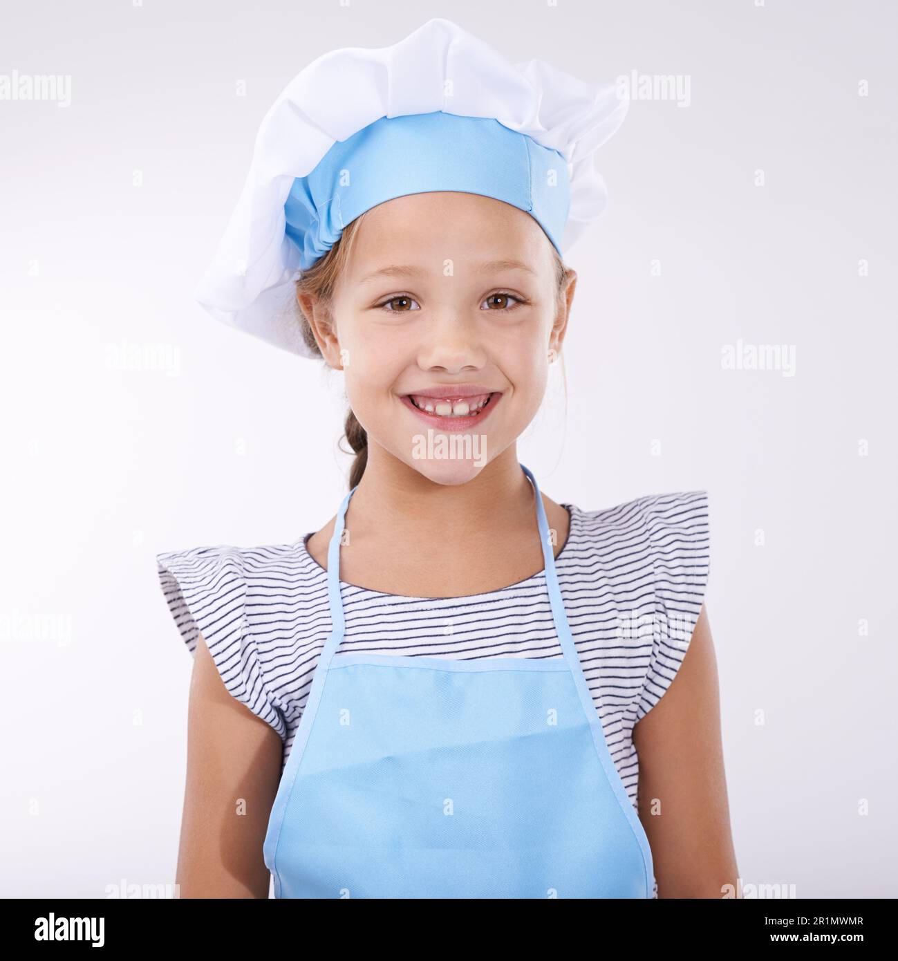 I cant wait to bake. A cute young girl in a chefs outfit standing ...