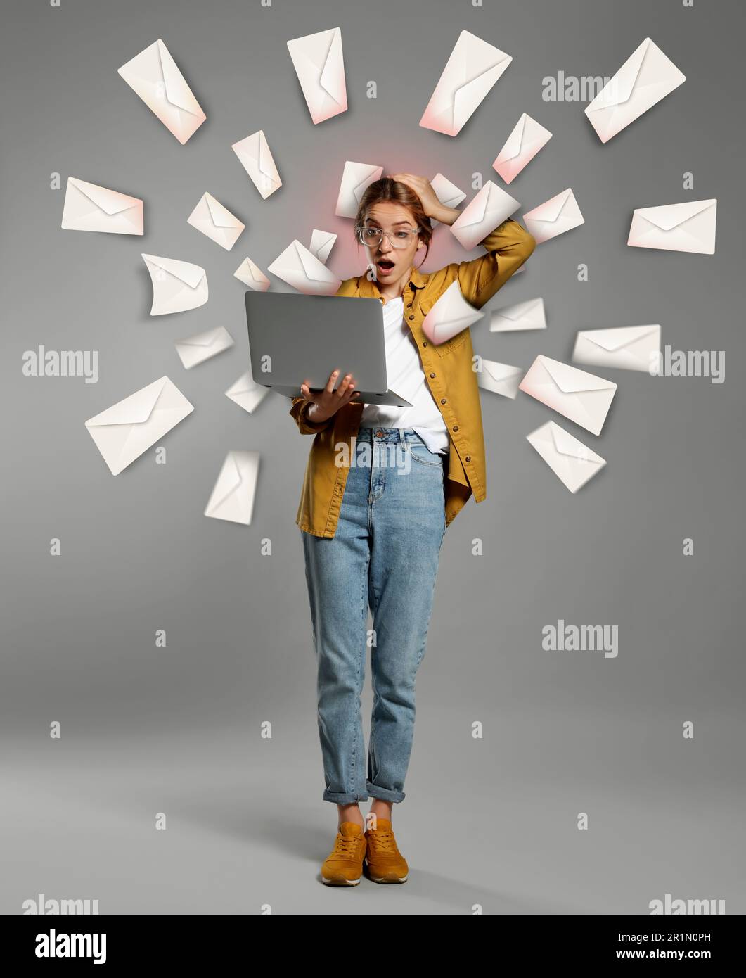 Email spam. Emotional young woman with laptop and many letters on grey ...
