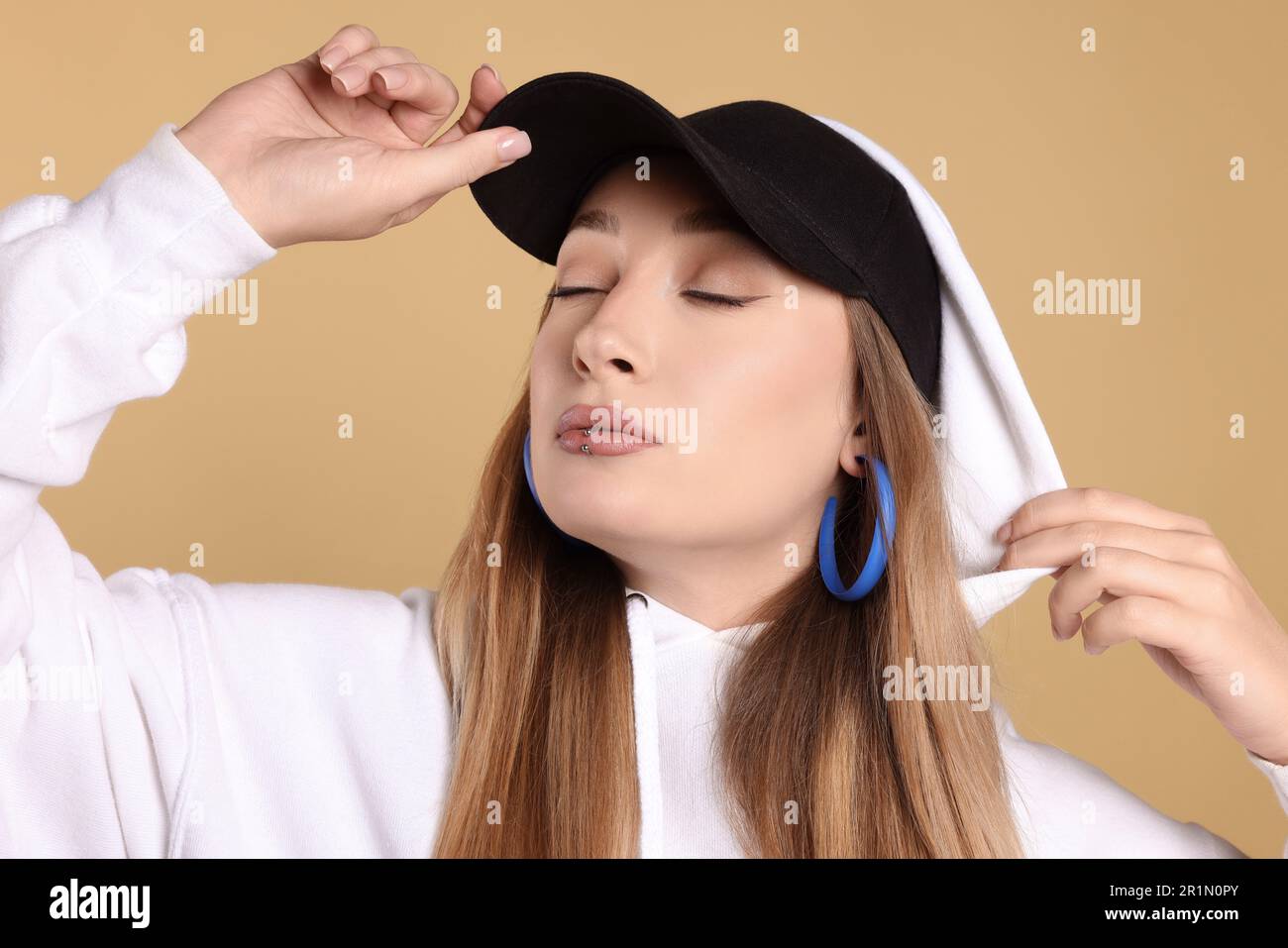 Young woman with lip piercing on beige background Stock Photo - Alamy