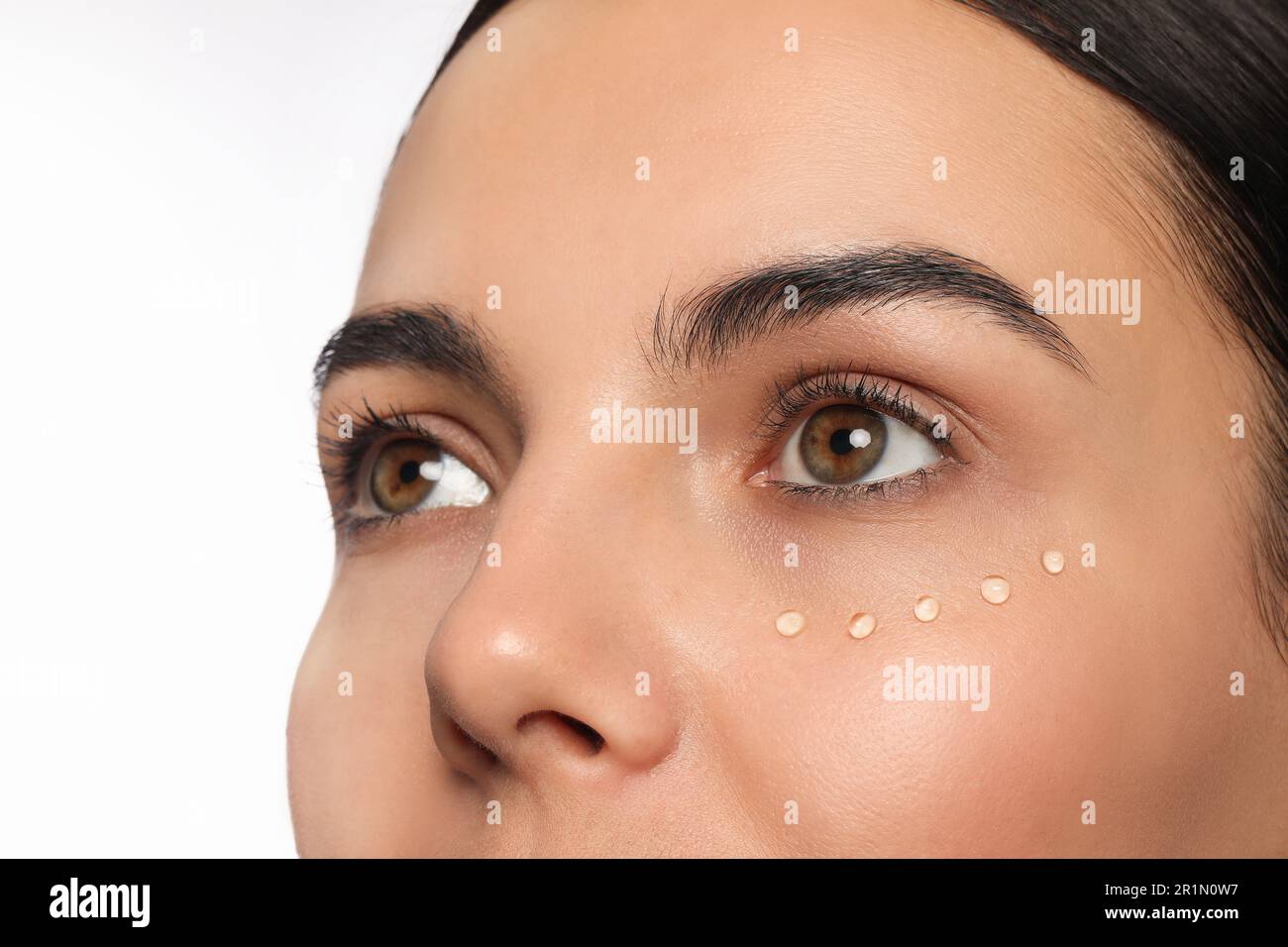 Closeup view of young woman with gel on skin under eye against white ...