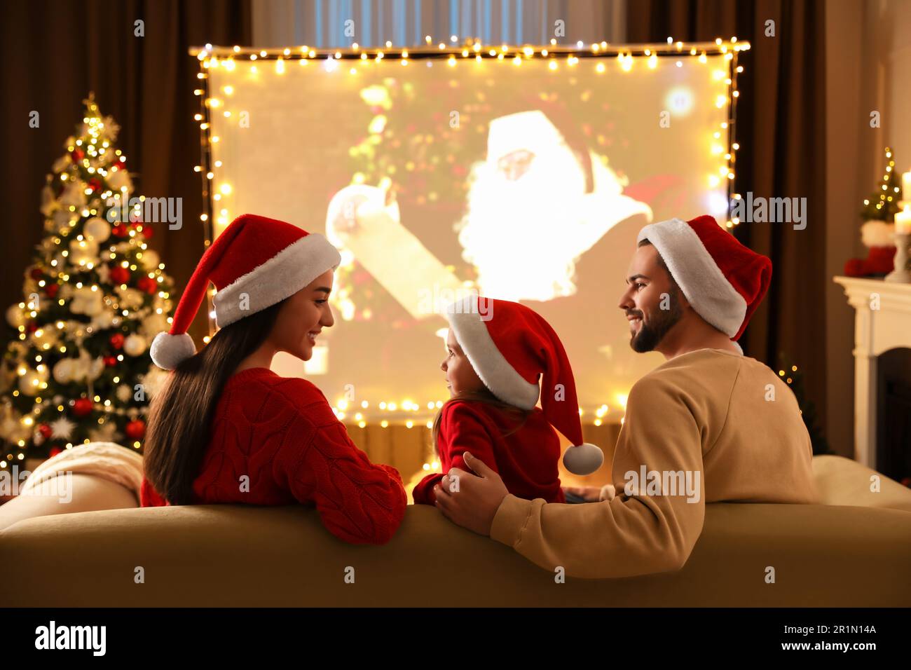 Family watching movie on projection screen in room decorated for ...