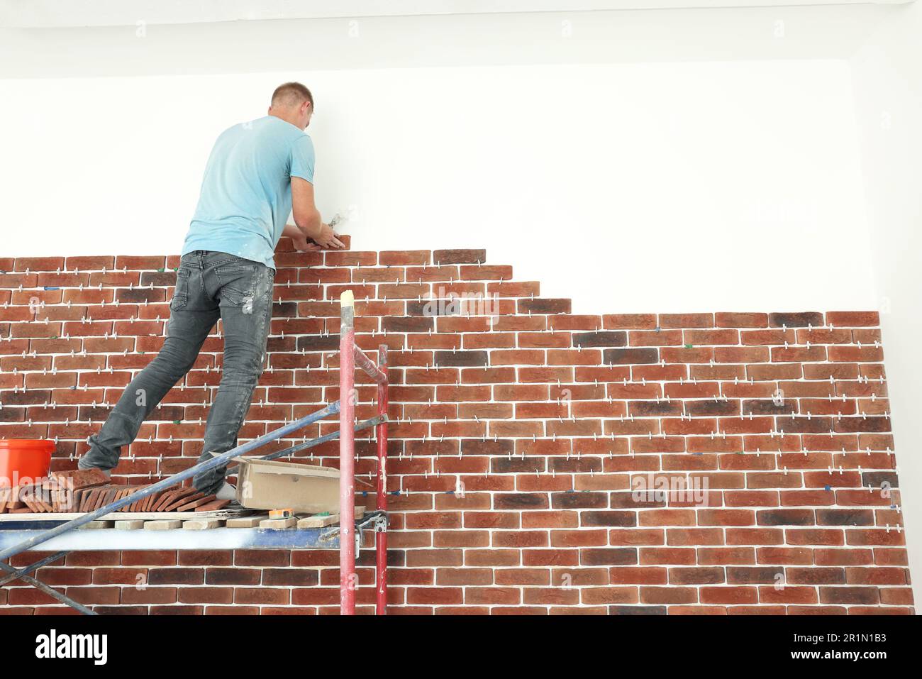 Professional builder gluing decorative bricks on wall indoors. Tiles ...