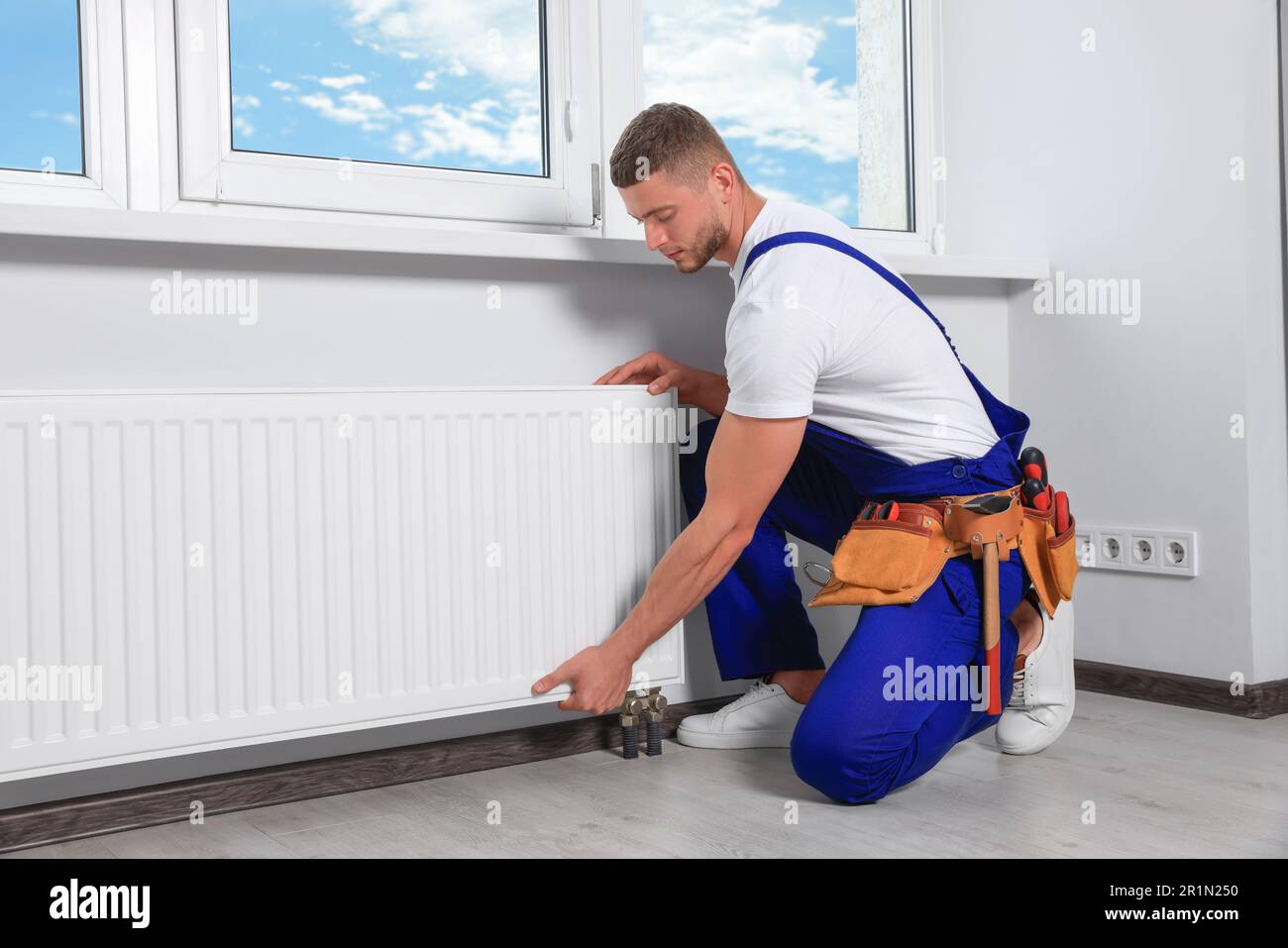 Professional plumber installing new heating radiator in room Stock ...
