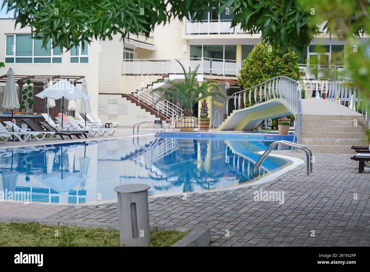 Outdoor swimming pool with handrails and many empty sunbeds at resort ...