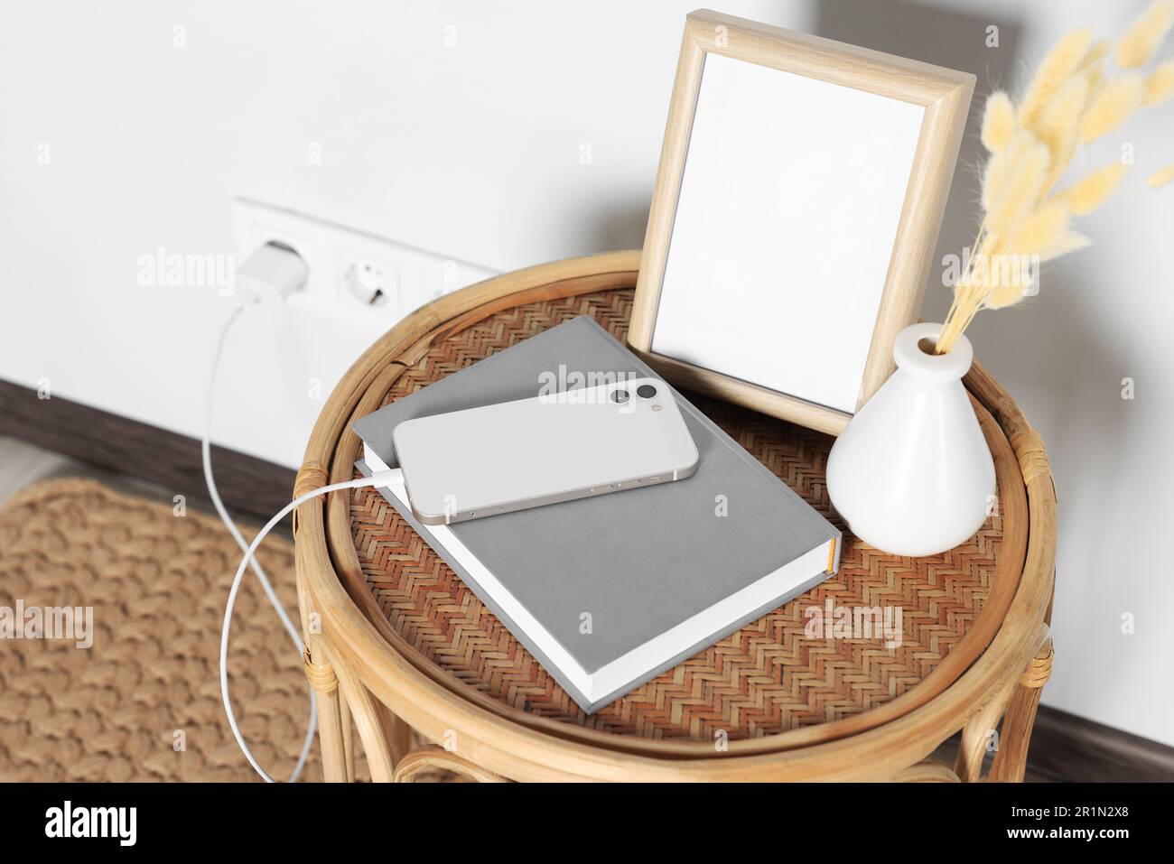 Modern smartphone charging on round rattan table indoors Stock Photo ...