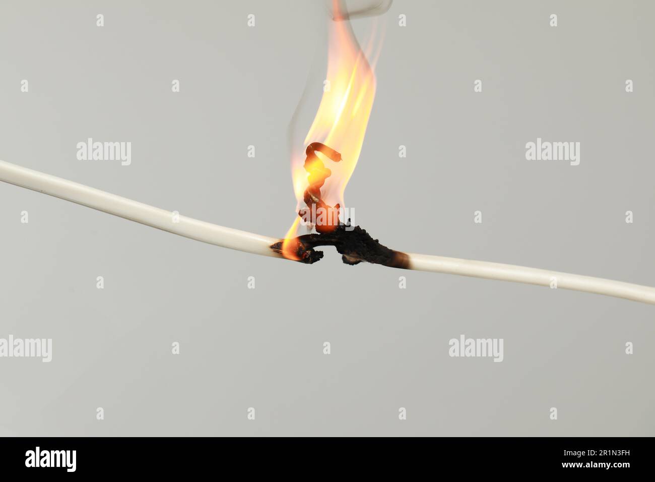 Inflamed white wire on grey background, closeup. Electrical short ...