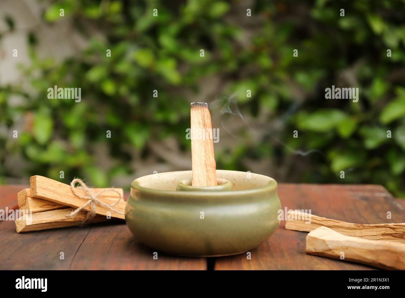 Palo Santo stick smoldering in holder on wooden table outdoors Stock ...