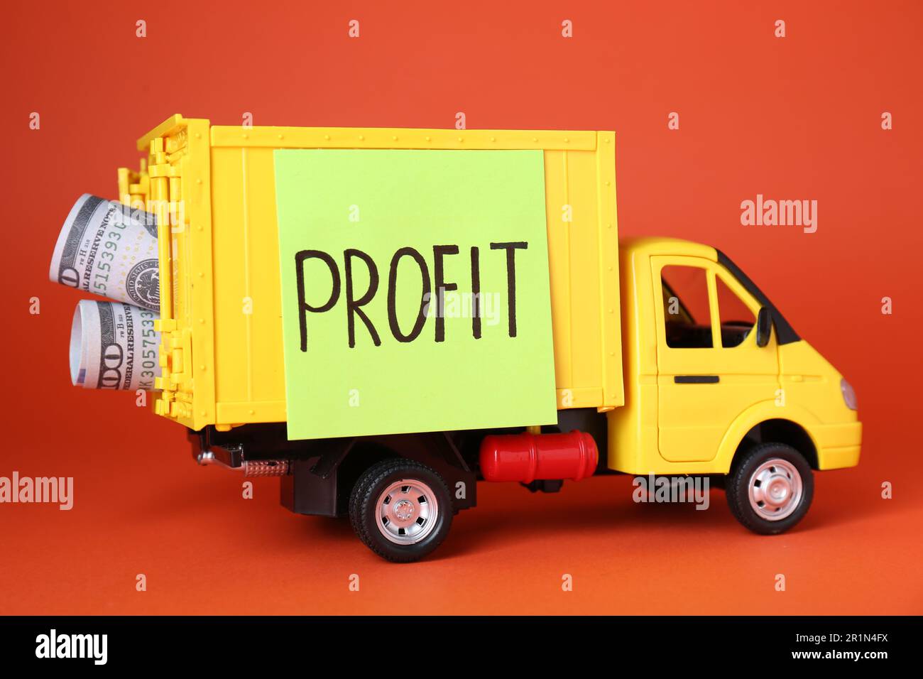 Economic profit concept. Toy truck with banknotes on red background ...