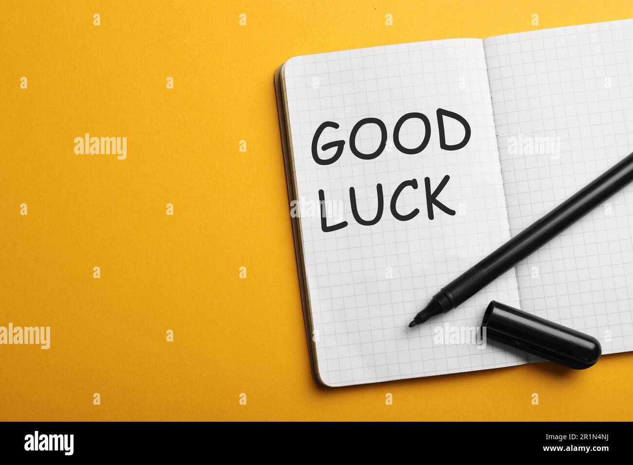 Open notebook with GOOD LUCK on orange background, top view. Space for ...