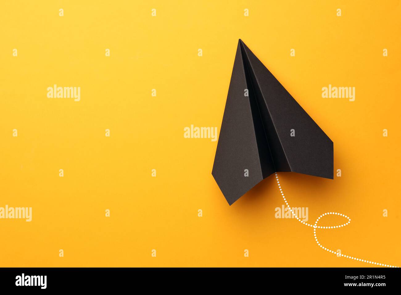 Handmade black paper plane on yellow background, top view. Space for ...