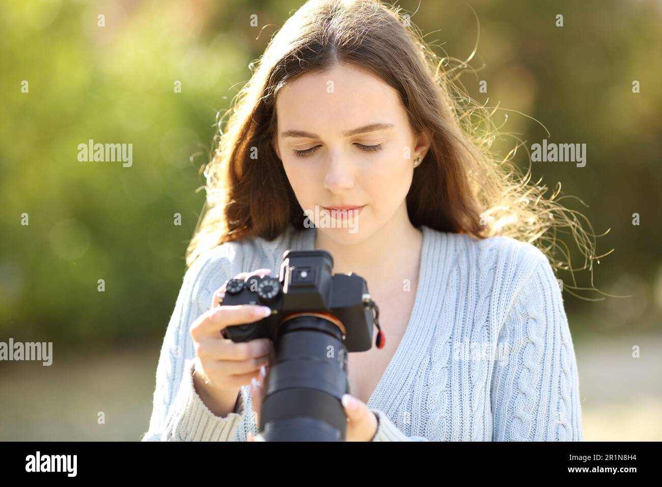 Serious photographer checks mirrorless camera screen in a park Stock ...