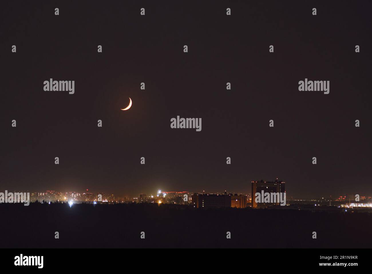 A crescent moon in the night sky is setting over the horizon. New moon ...