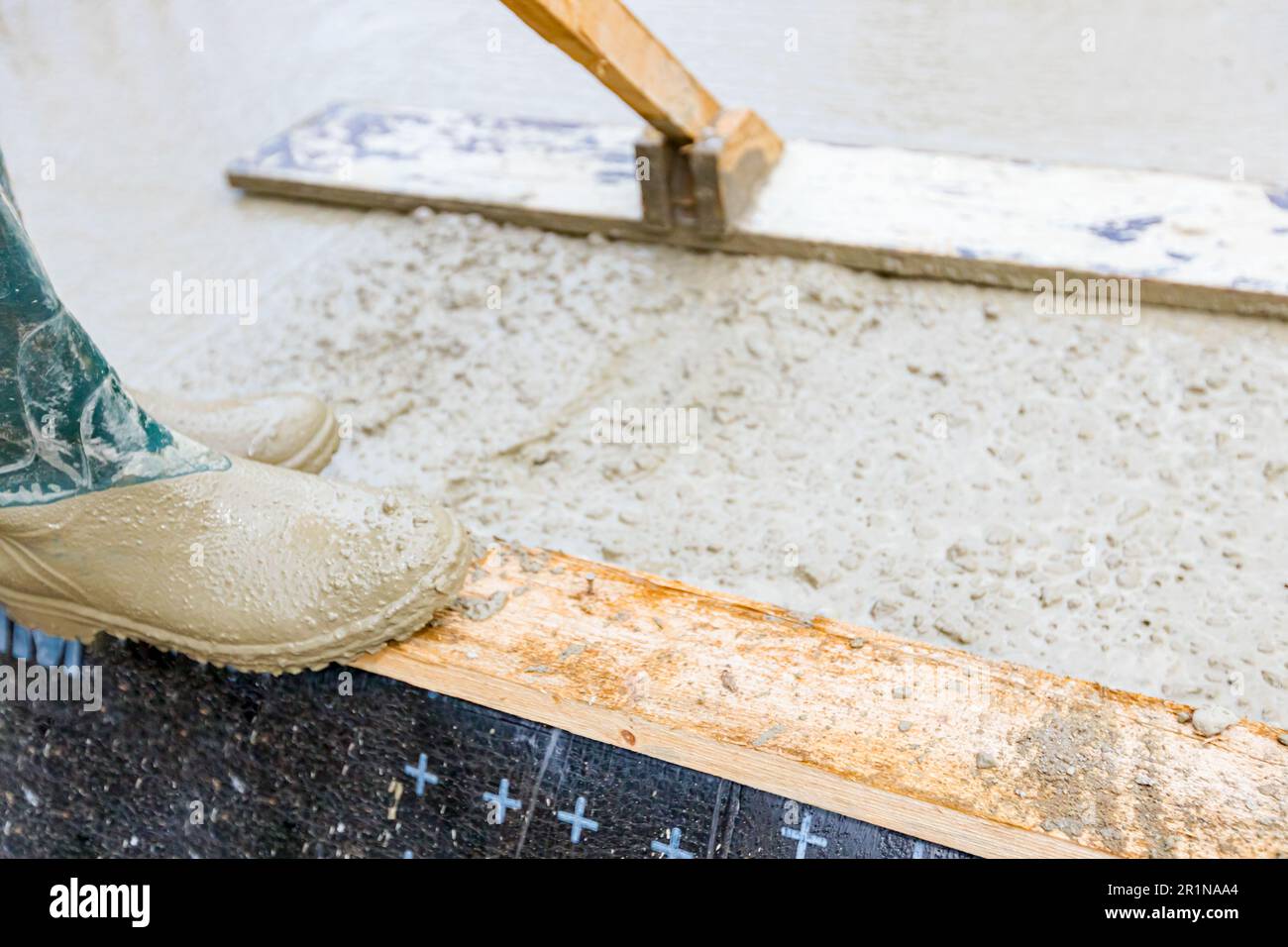 Rigger in rubber boots, worker is using wooden handmade handcraft tool ...