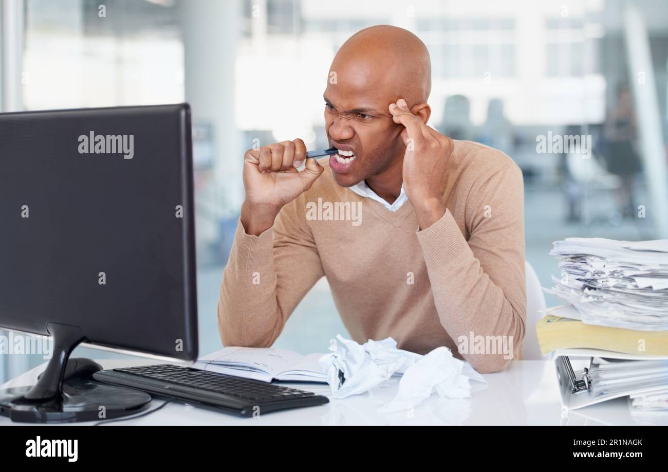Stress, computer and burnout with a business man biting his pen at a ...
