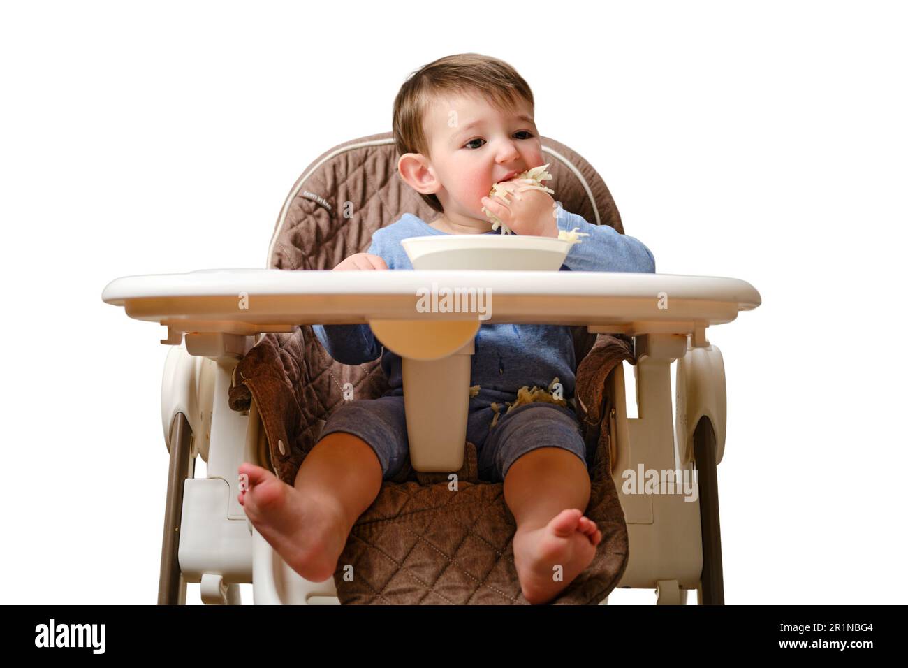 A funny child is eating a grated apple with his mouth full while ...