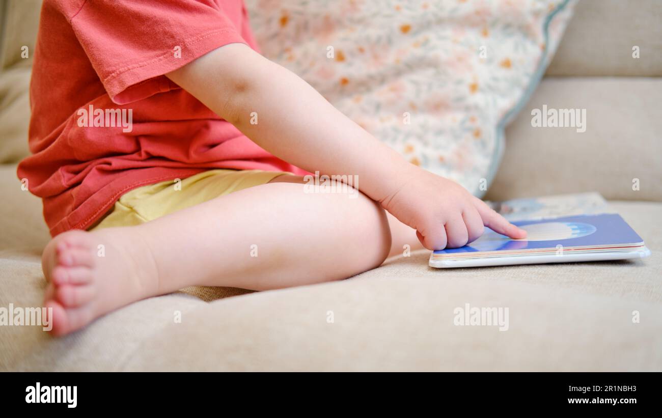 The cute baby is playing with the colorful picture book, flipping ...