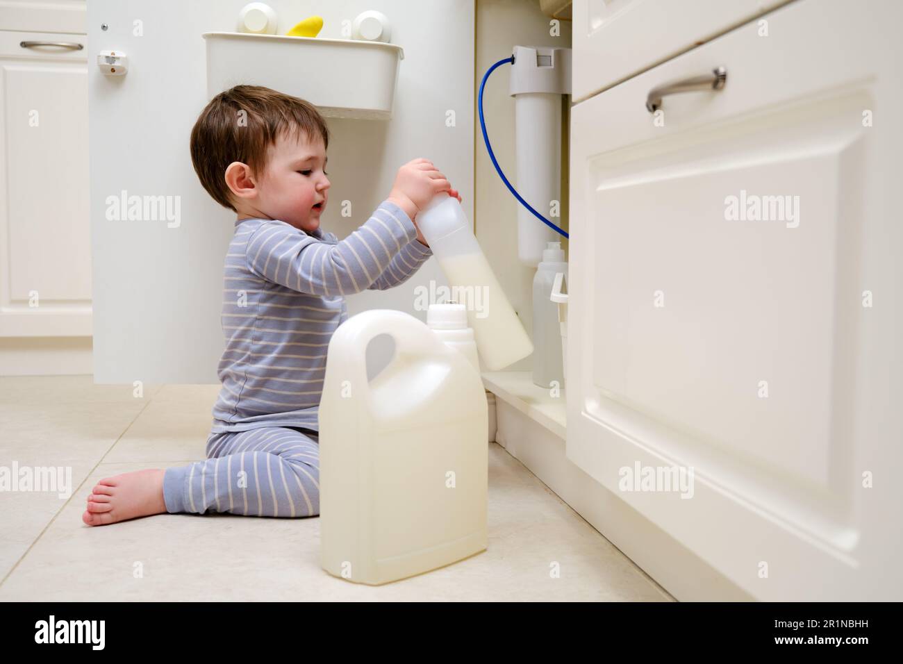 A child is playing with chemical cleaning products under the sink in ...