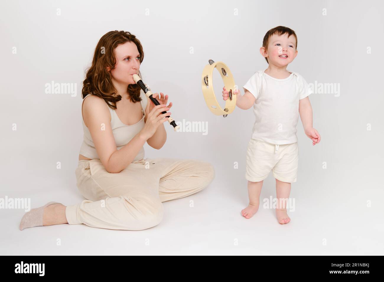 Happy baby with mother play musical instruments on studio white ...