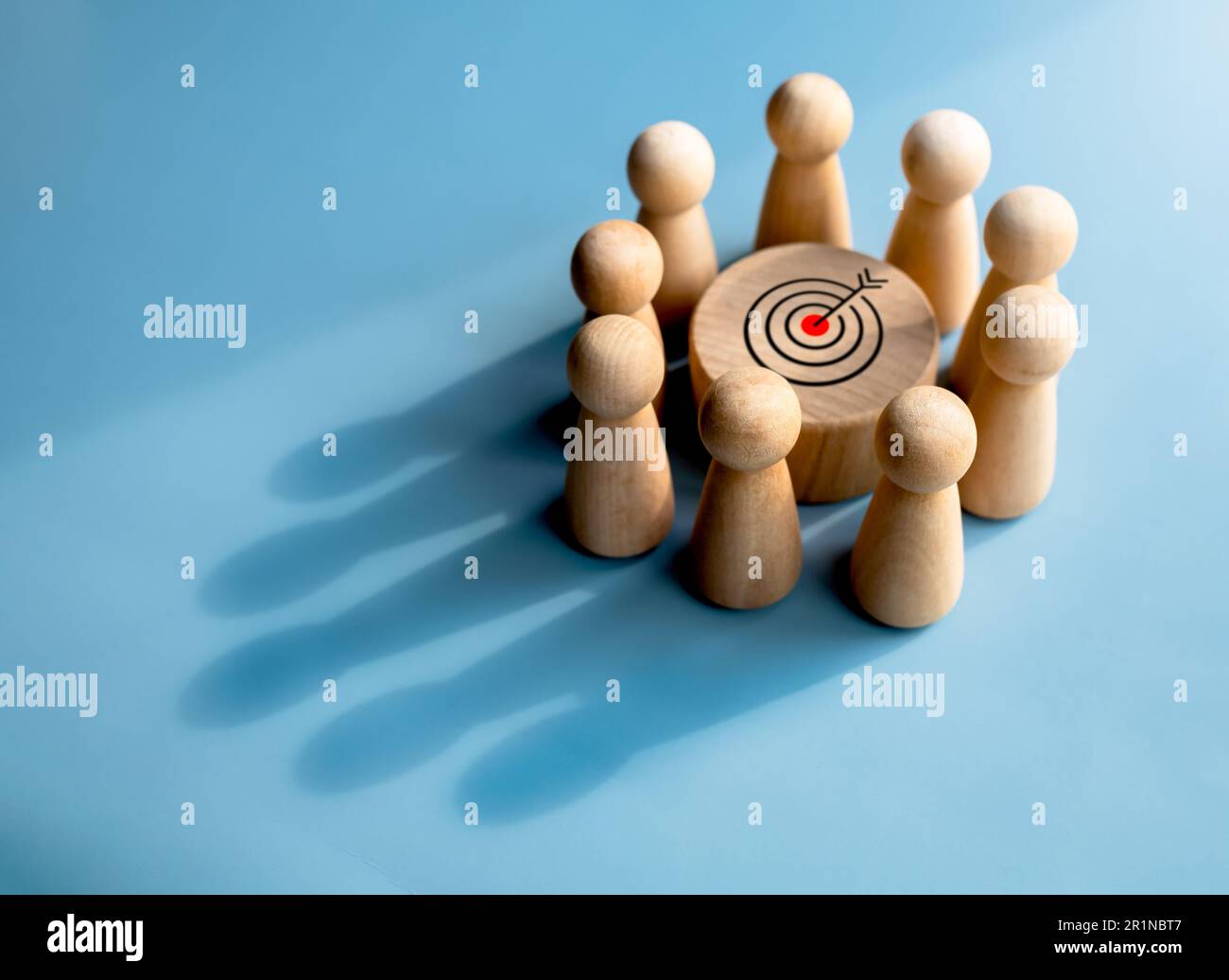 Target icon on round wood block surrounded with small wooden human ...
