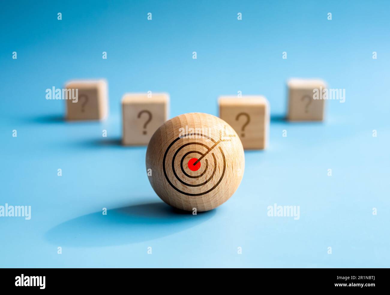 Wood sphere with target icon in front of the wooden cube blocks with question mark symbol on ...