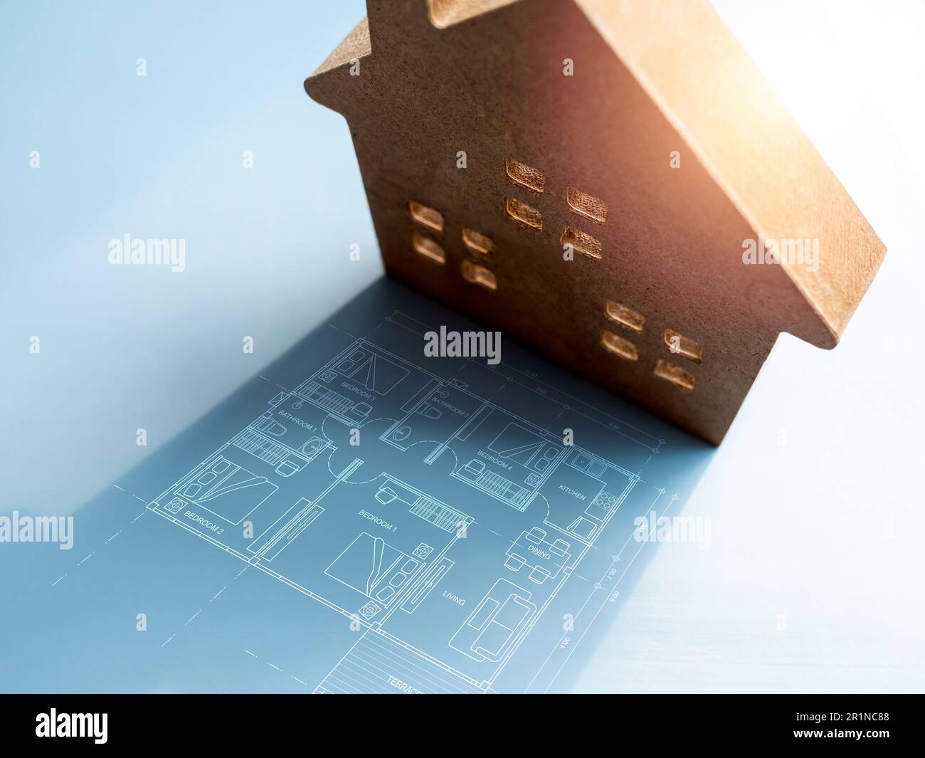 Home floor plan in the shadow near the small wooden house model on blue ...