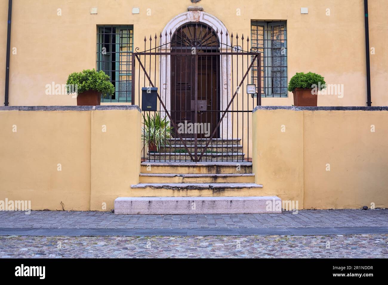 Door behind a gate next to a staircase in a square in an italian town ...