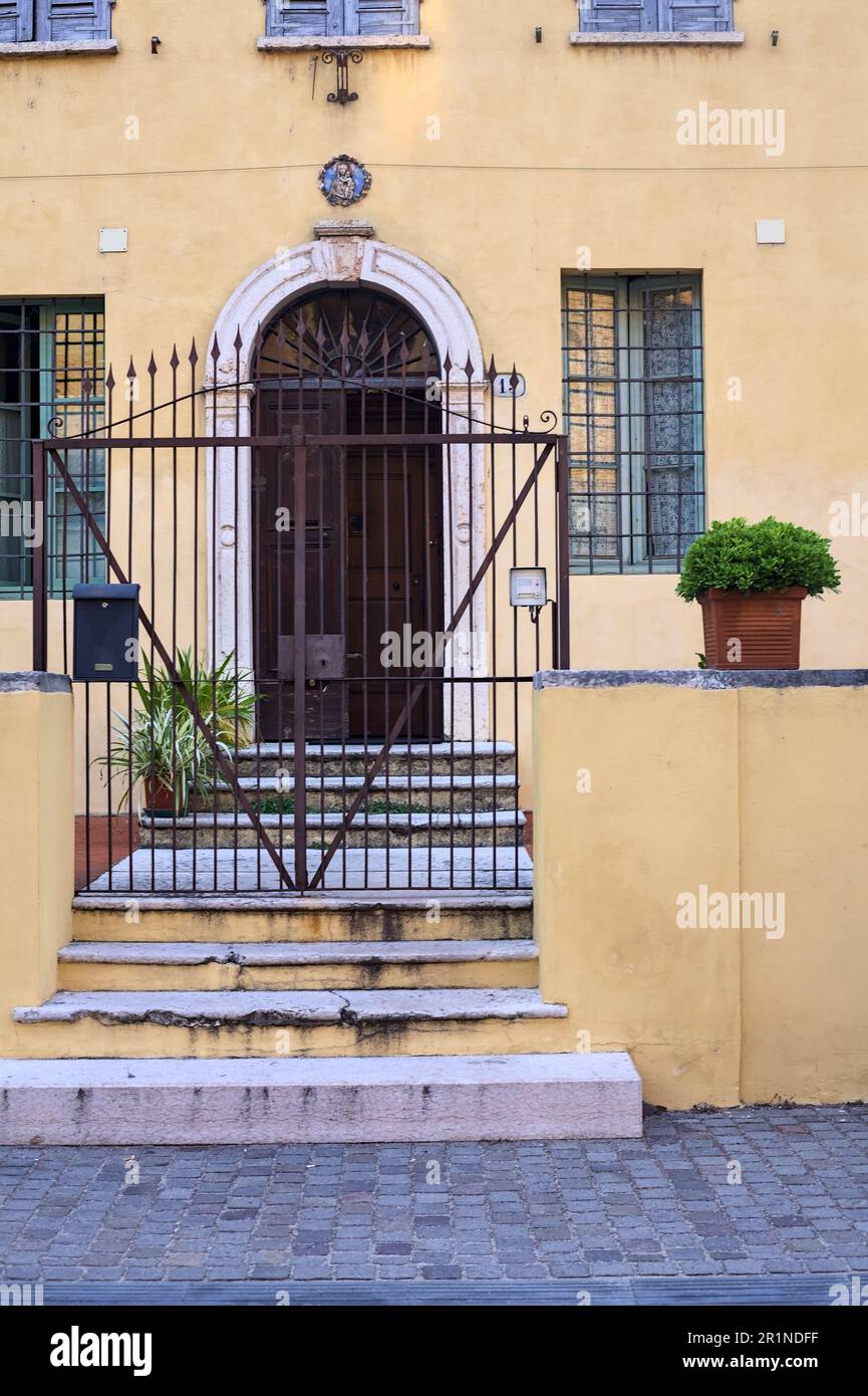 Door behind a gate next to a staircase in a square in an italian town ...
