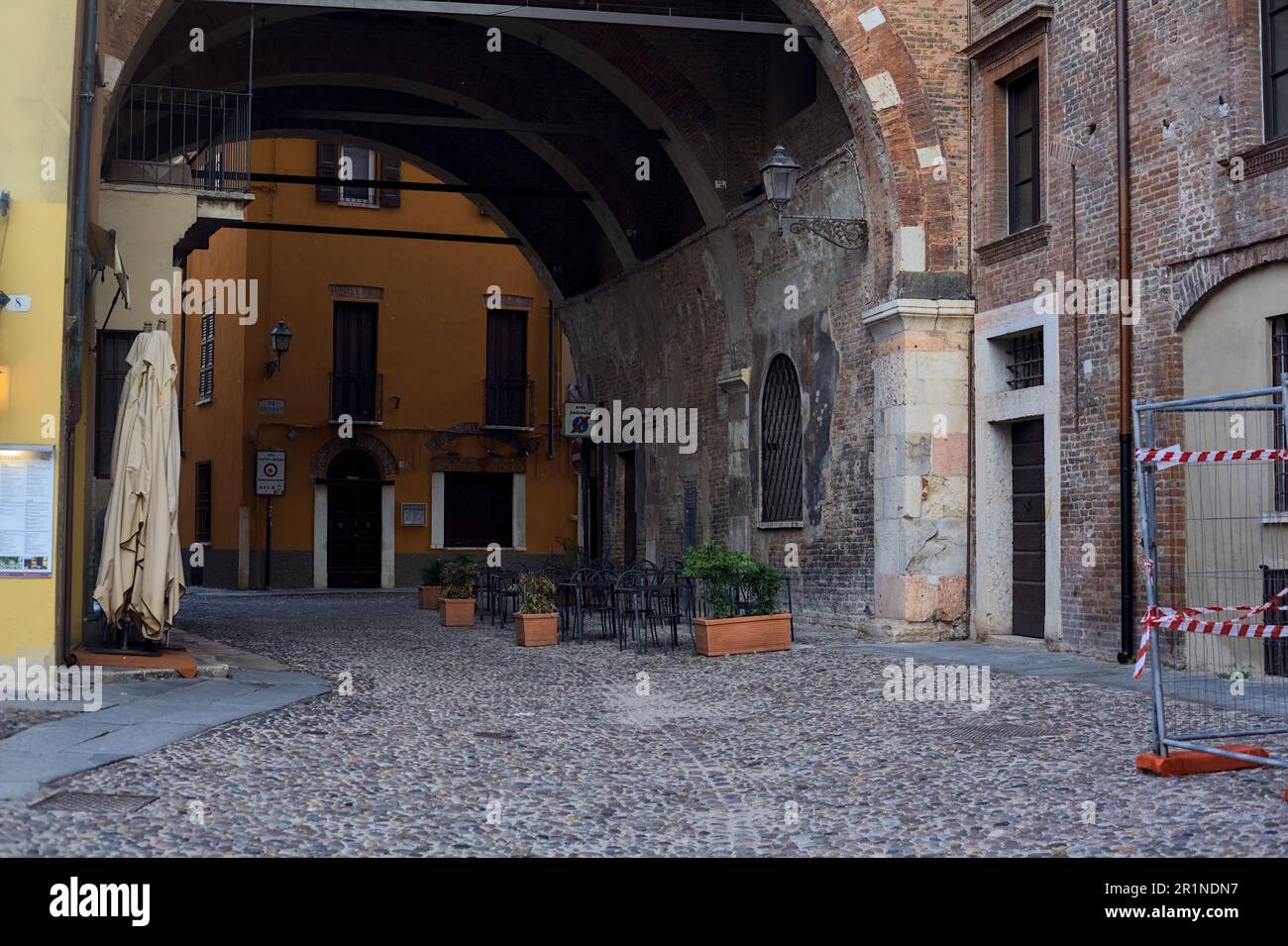 Covered alley under a palace with tables and chairs in an italian town ...
