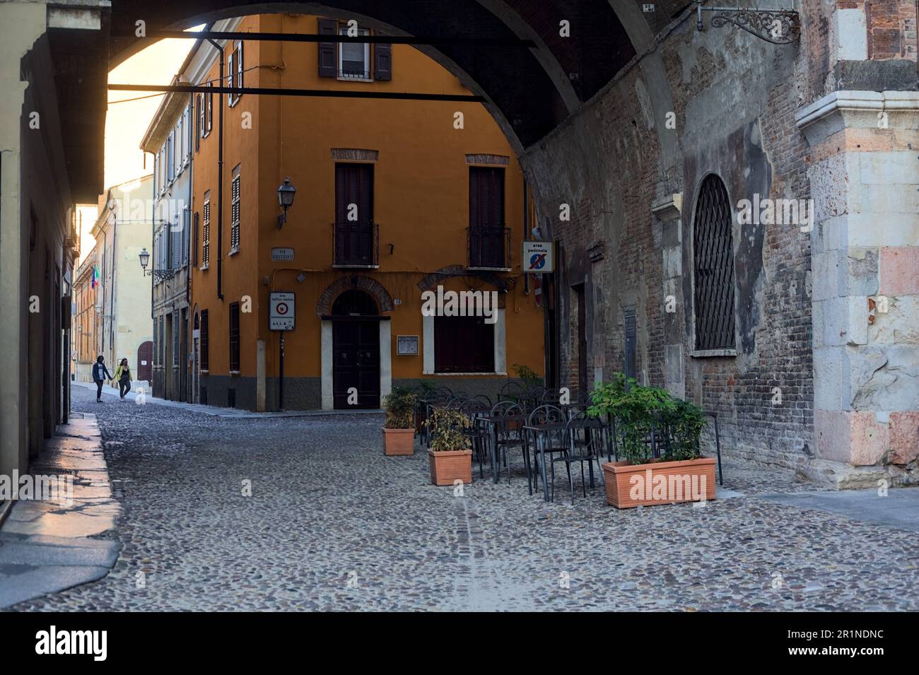 Covered alley under a palace with tables and chairs in an italian town ...