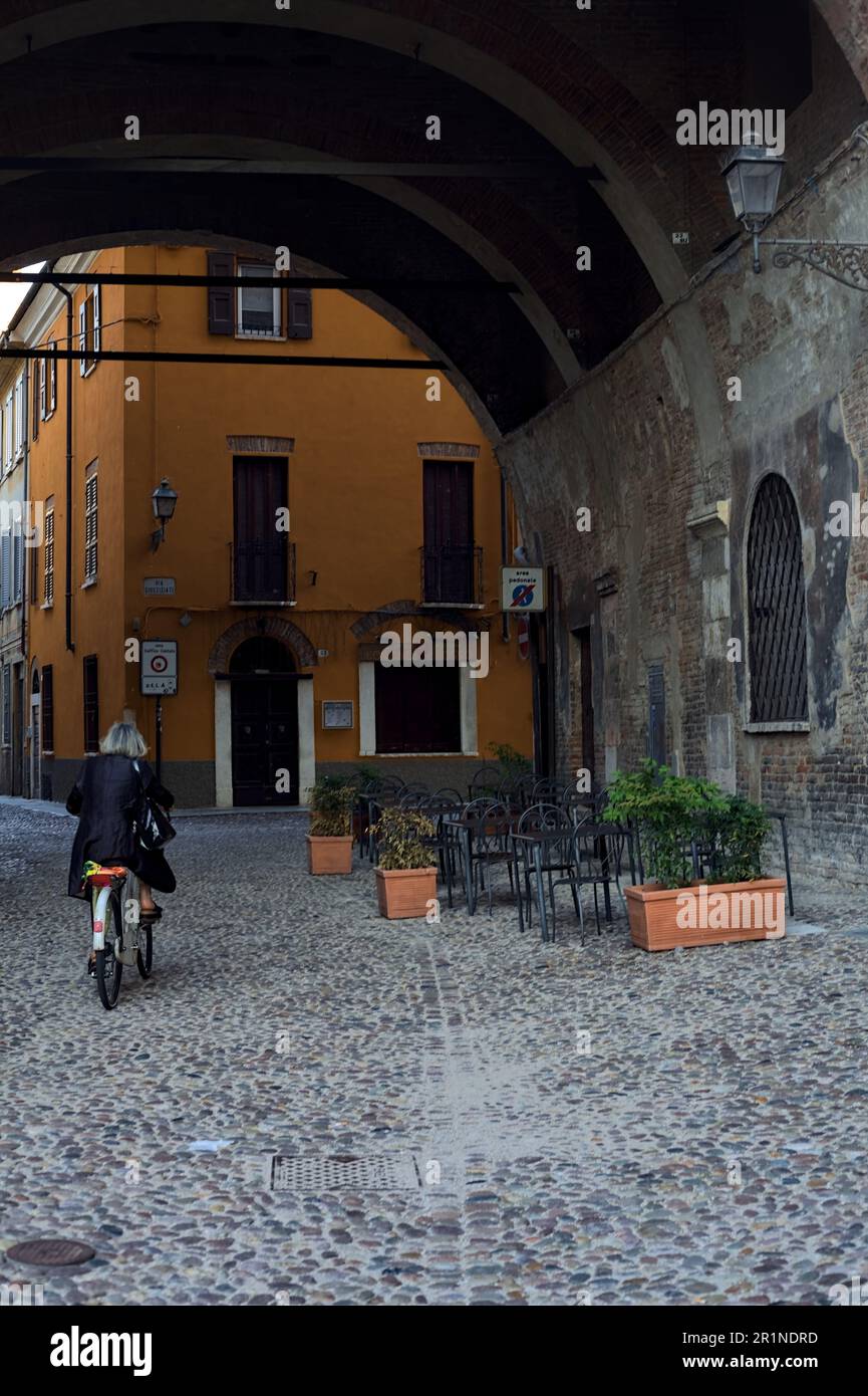 Covered alley under a palace with tables and chairs in an italian town ...