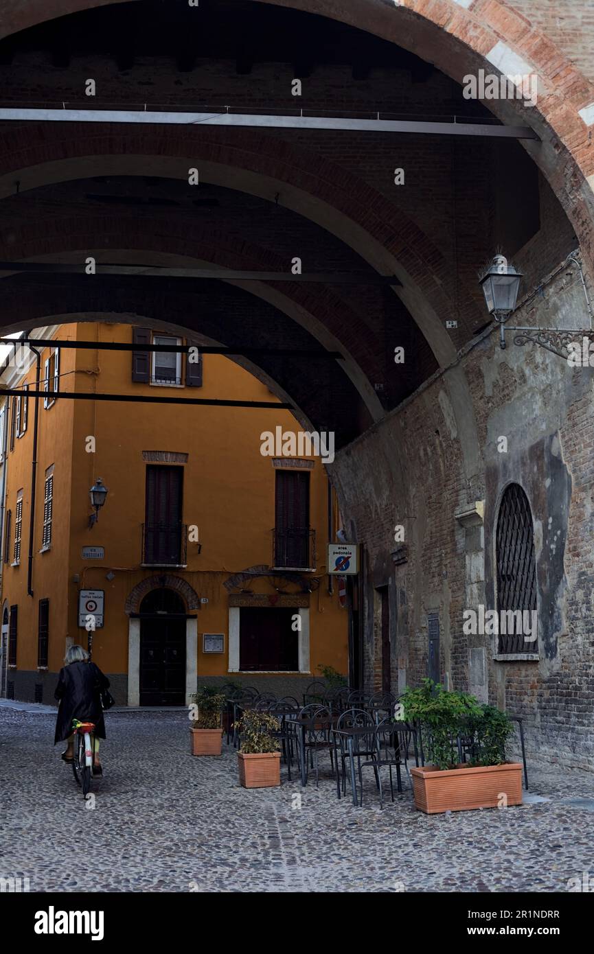 Covered alley under a palace with tables and chairs in an italian town ...