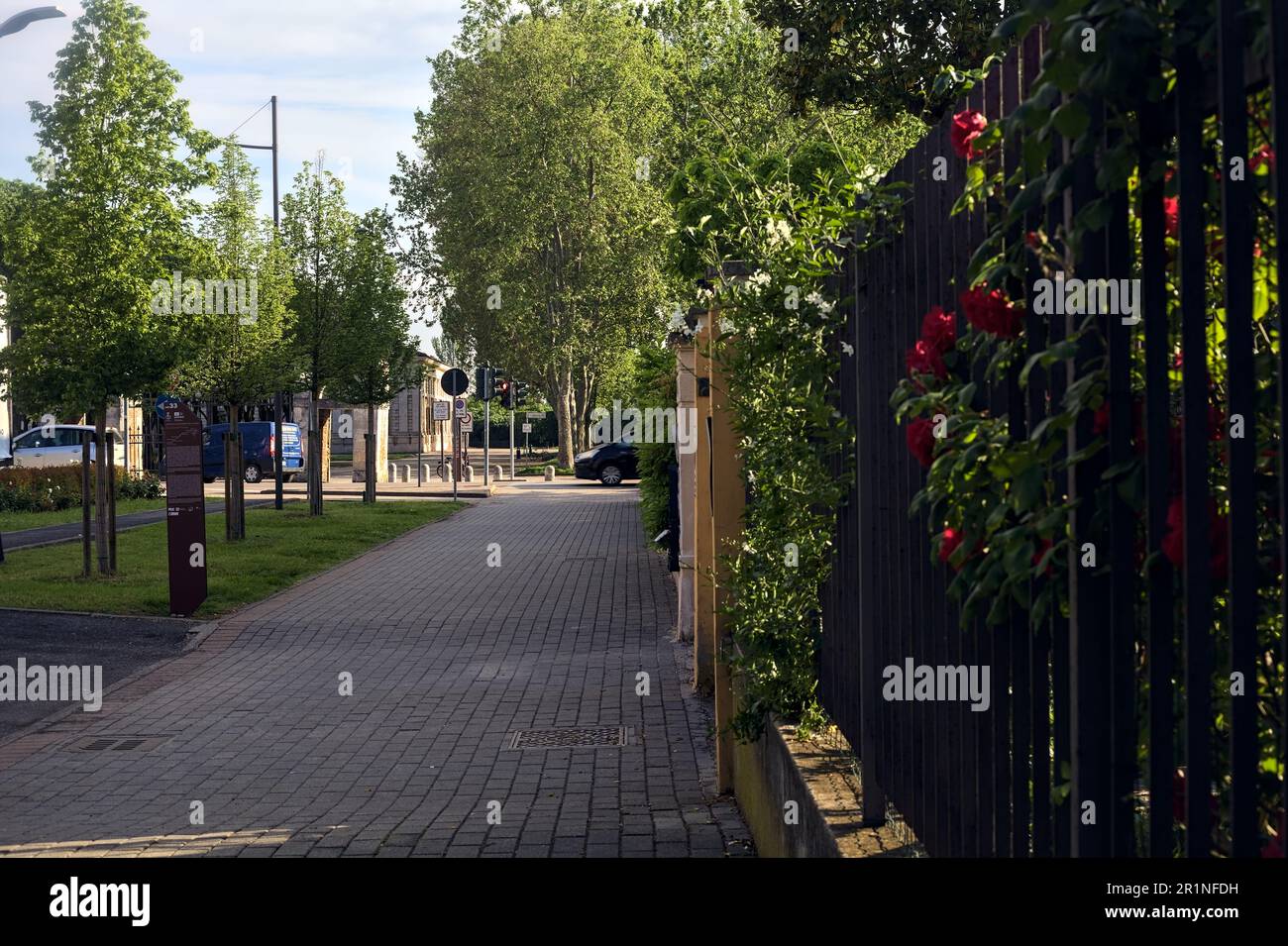 Pavement next to a fence with flowers and trees in an italian town at ...