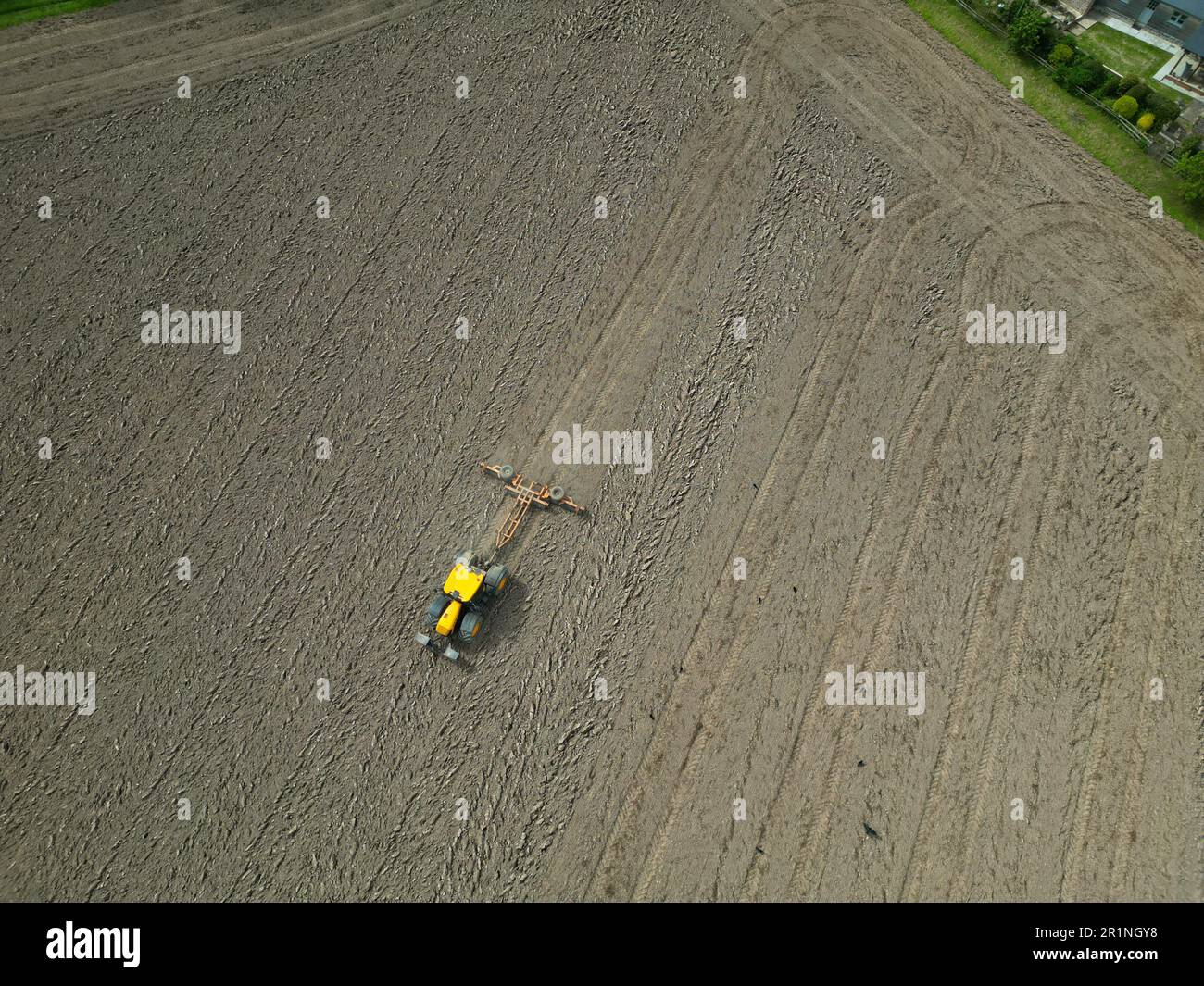 Aerial view of farm tractor working a field in preparation for planting ...