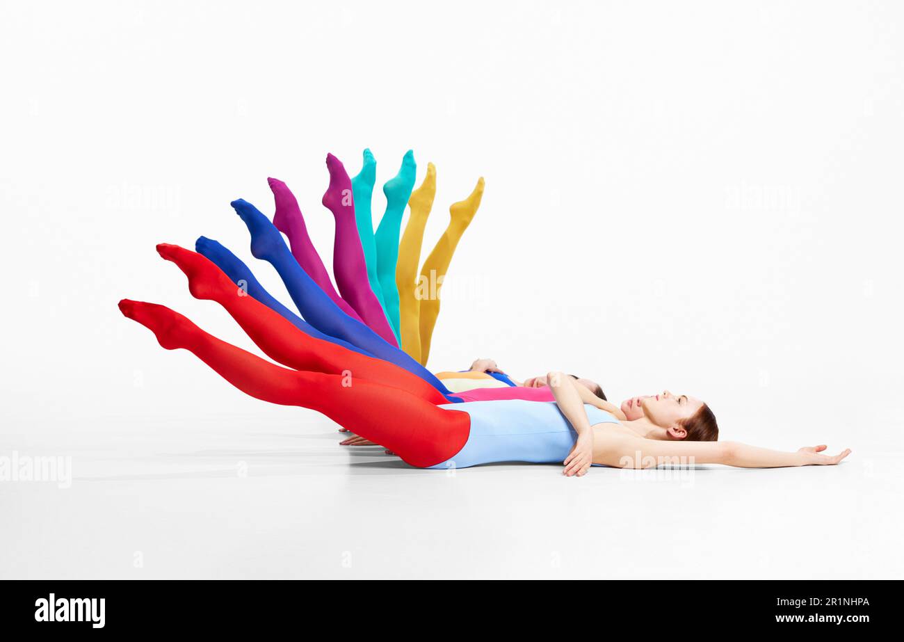 Rainbow. Group of young girls in bright tights lying on floor, raising ...