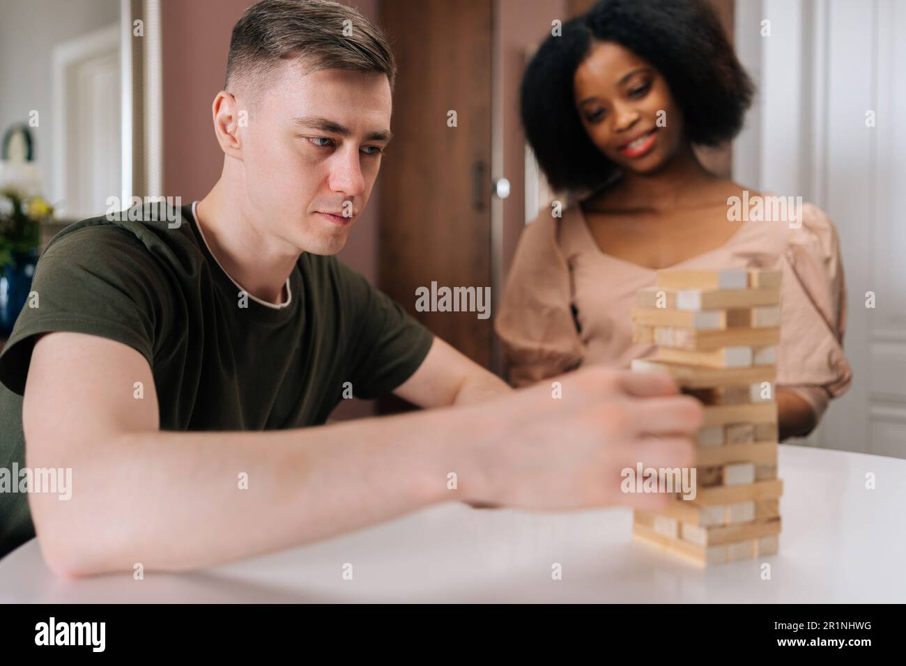 Closeup face of focused young man removing block from tower while ...