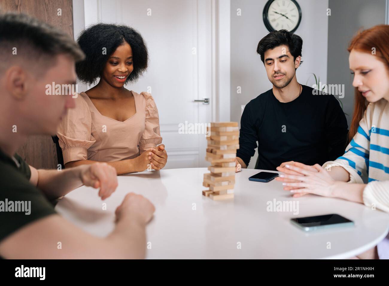 Multiethnic group of cheerful friends enjoying leisure logic game ...