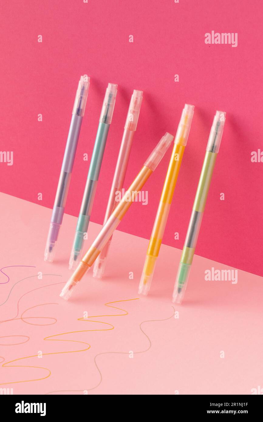 Colored markers stand against a pink background. Art concept ...