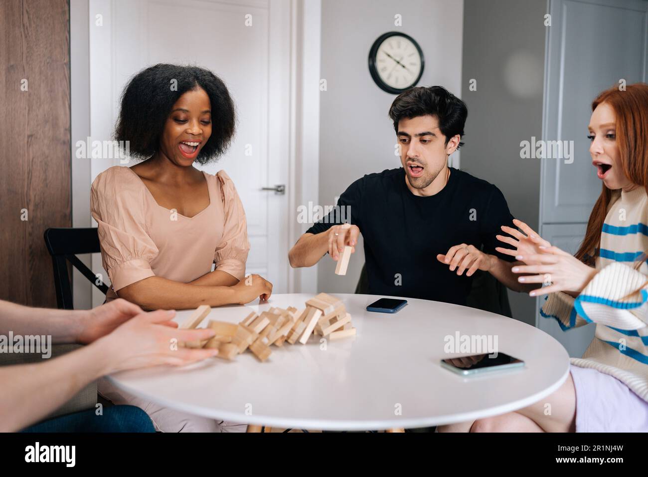 Cheerful multiethnic friends playing crash and stack board game ...