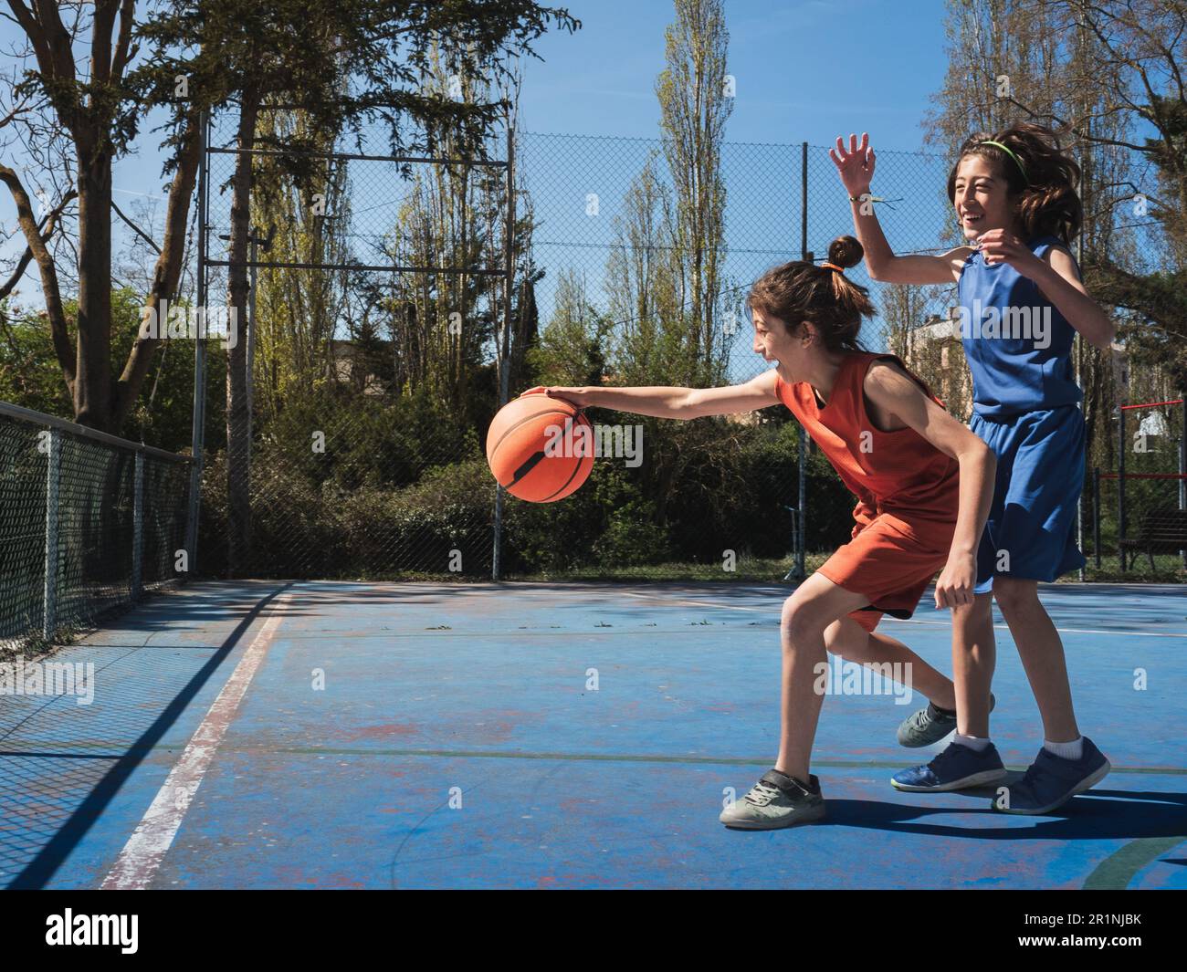 Two brothers enjoy playing basketball on an outdoor court. They take ...