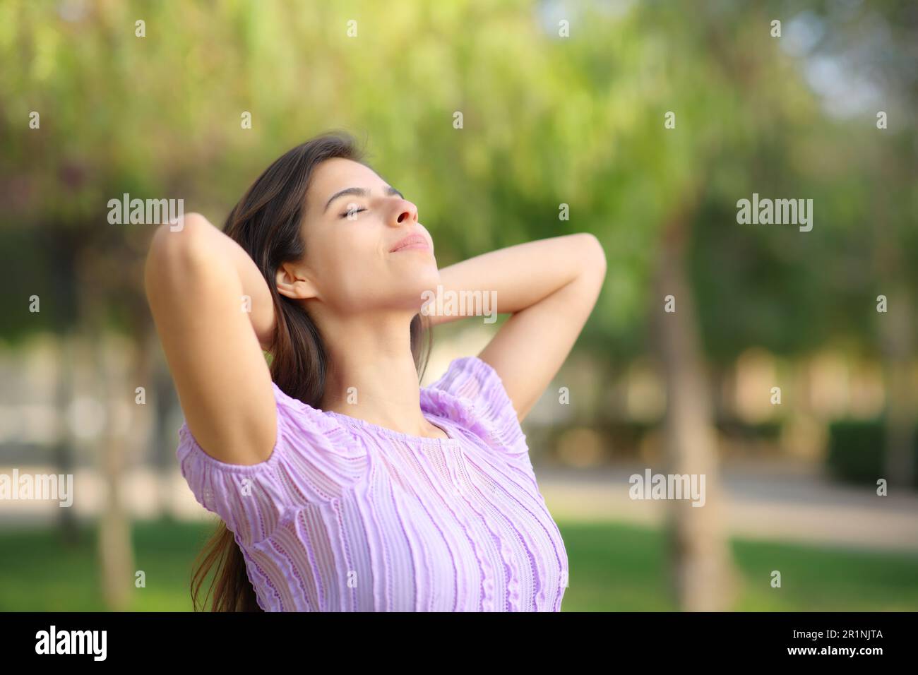 Woman relaxing breathing fresh air with hands on head standing in a ...